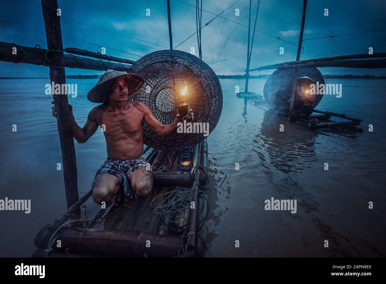 Asian fisherman holding a lantern on his boat waiting to fish in the ...