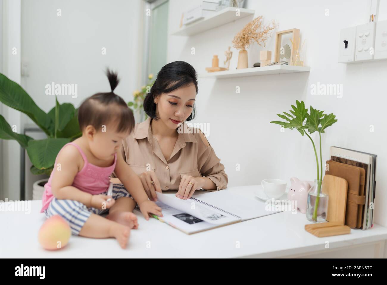 Little assistant. Little baby girl using pen while sitting on office ...