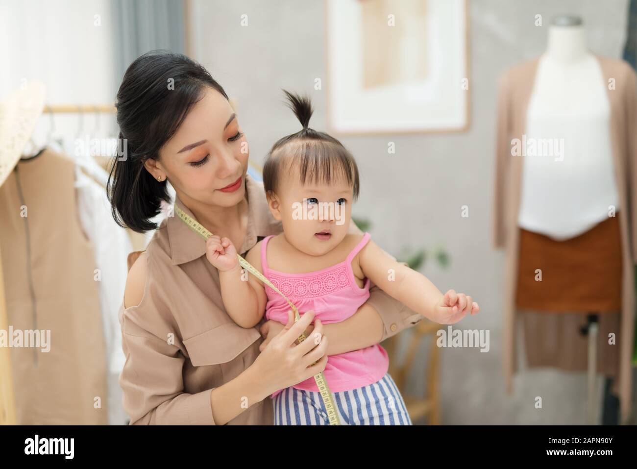 Working together. Young beautiful designer standing near her baby girl ...