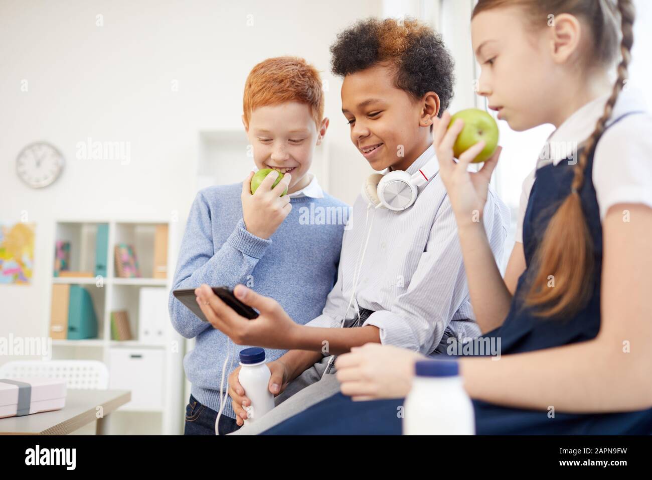 Group of school children eating milk and drinking fruit and using ...