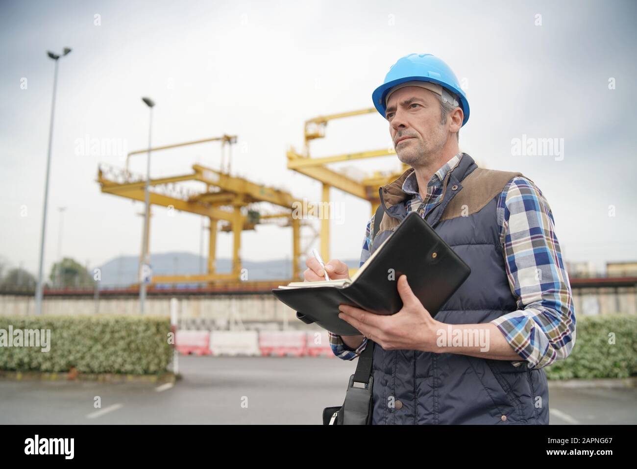 Mature construction worker inspecting work sight with notebook Stock ...