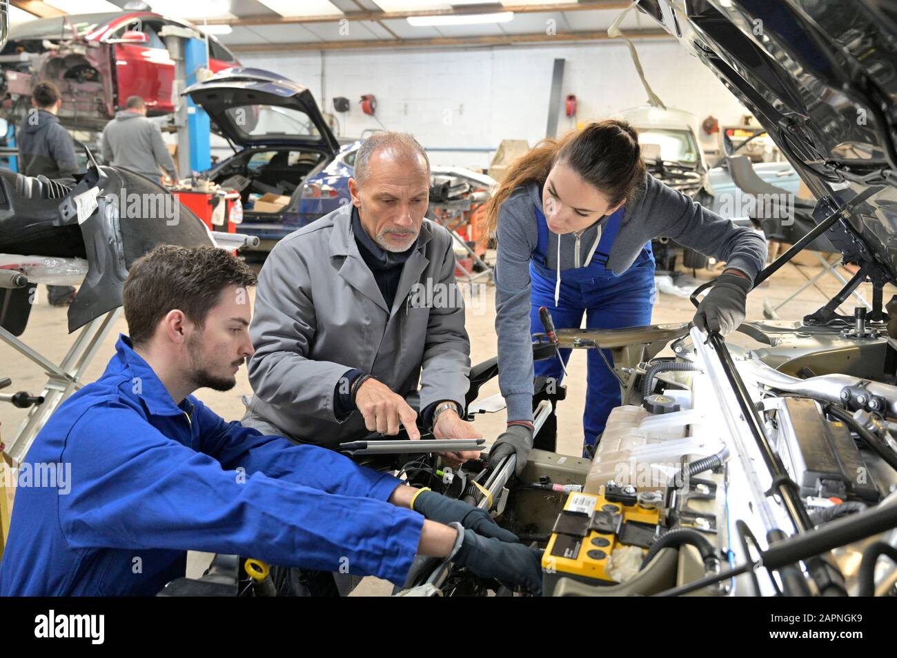 Instructor with trainees working on car engine Stock Photo - Alamy