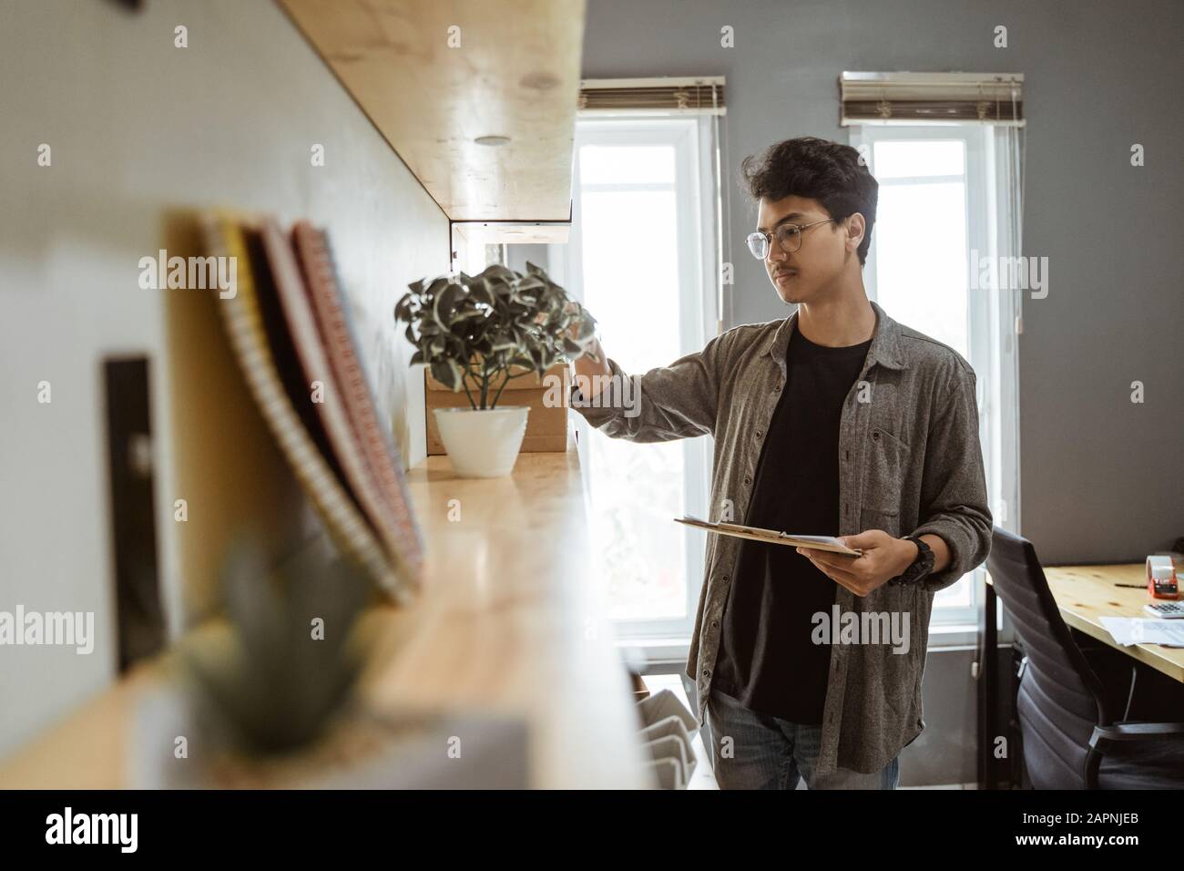 Young asian worker to arrange goods on rack in the office room Stock ...