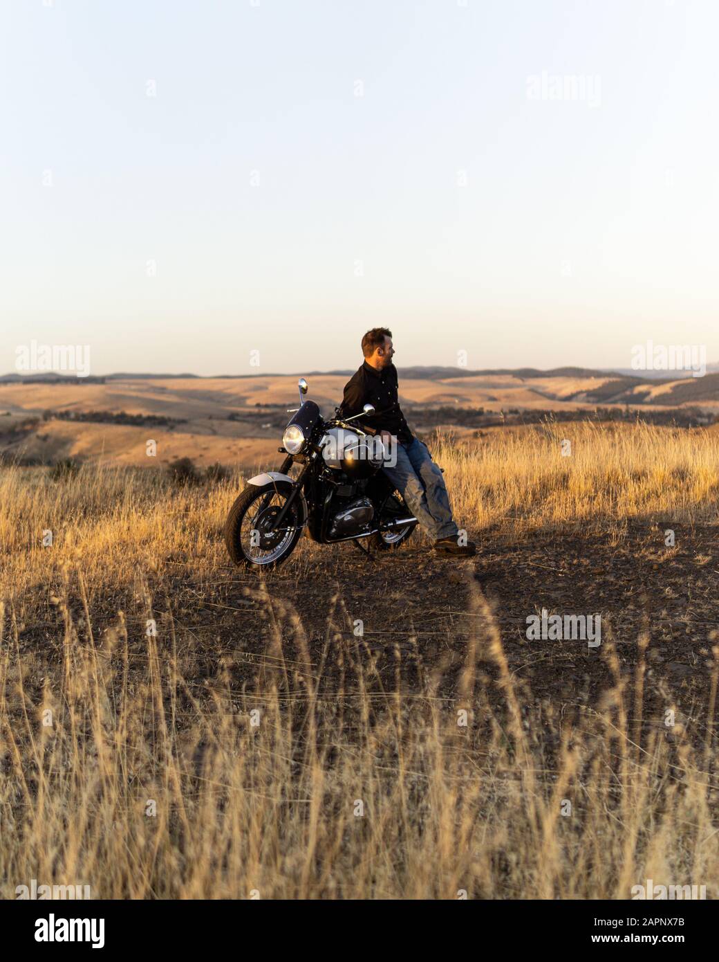 Man and vintage motorcycle in the country at sunset Stock Photo - Alamy