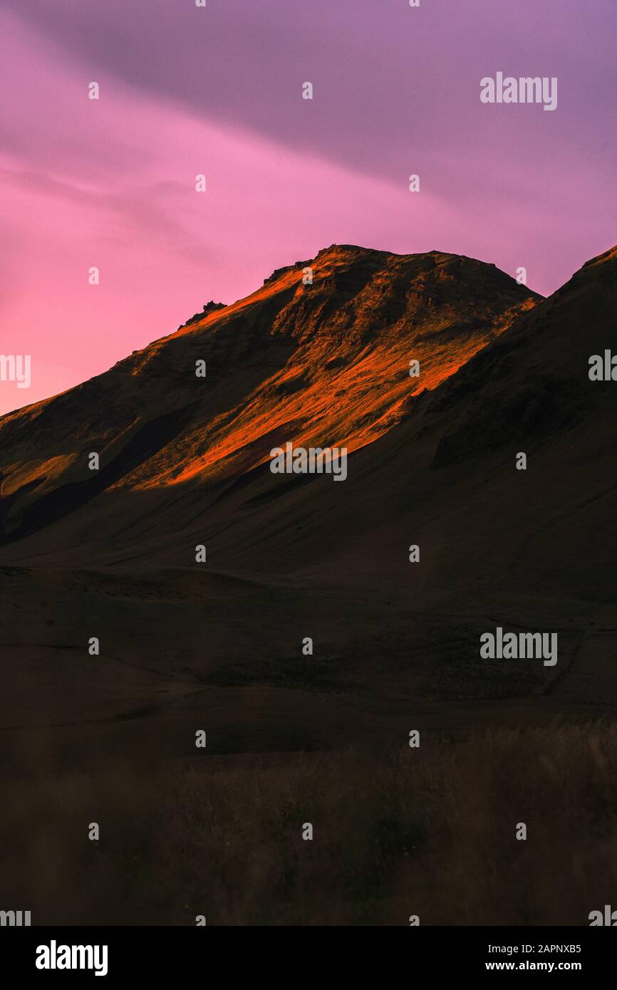 Beautiful scenic sunset in Iceland. Yellow lit mountain side with pink ...