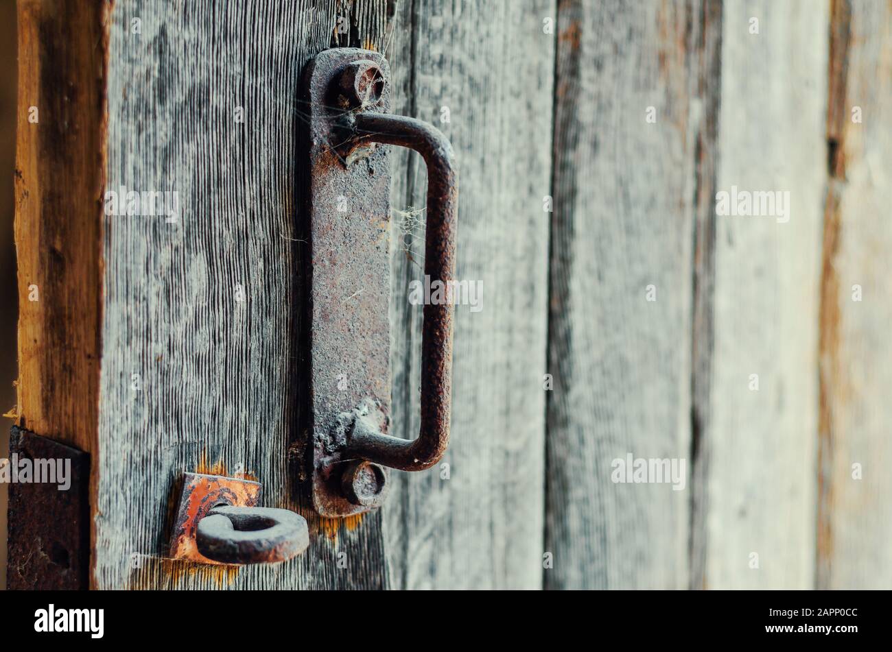 Old rusty deadbolt handle on a weathered wooden door Stock Photo - Alamy