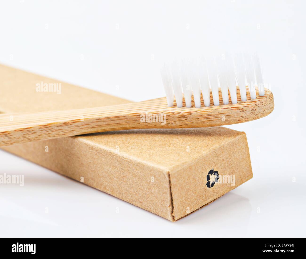 Bamboo toothbrushes on brown paper box with recycle sign on white ...