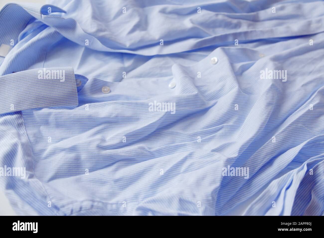 Blue cotton wrinkled and rumpled shirt on white. Washed shirt after ...