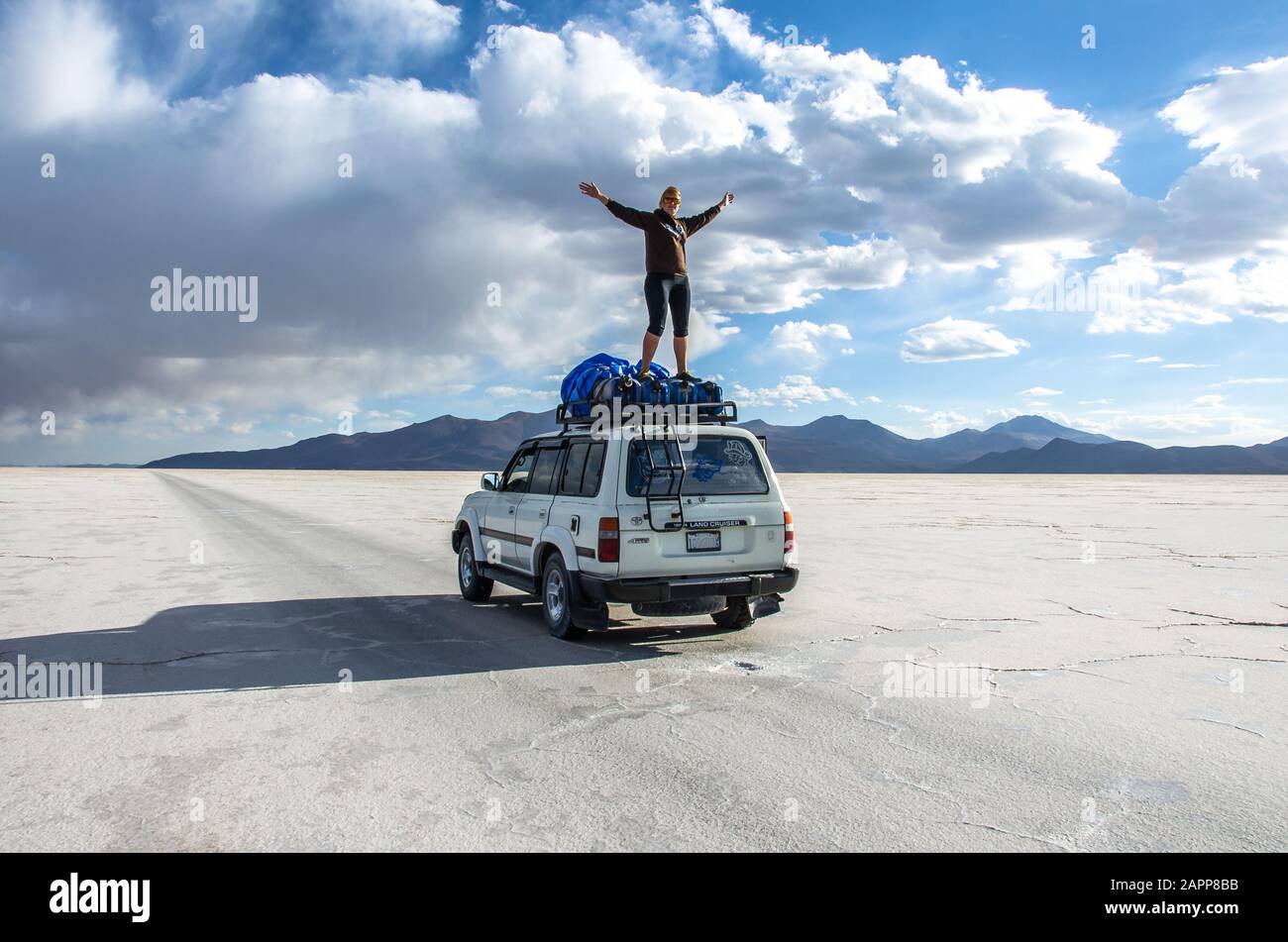 Salar de Uyuni in Bolivia covered with car and clouds. Girl standing on ...