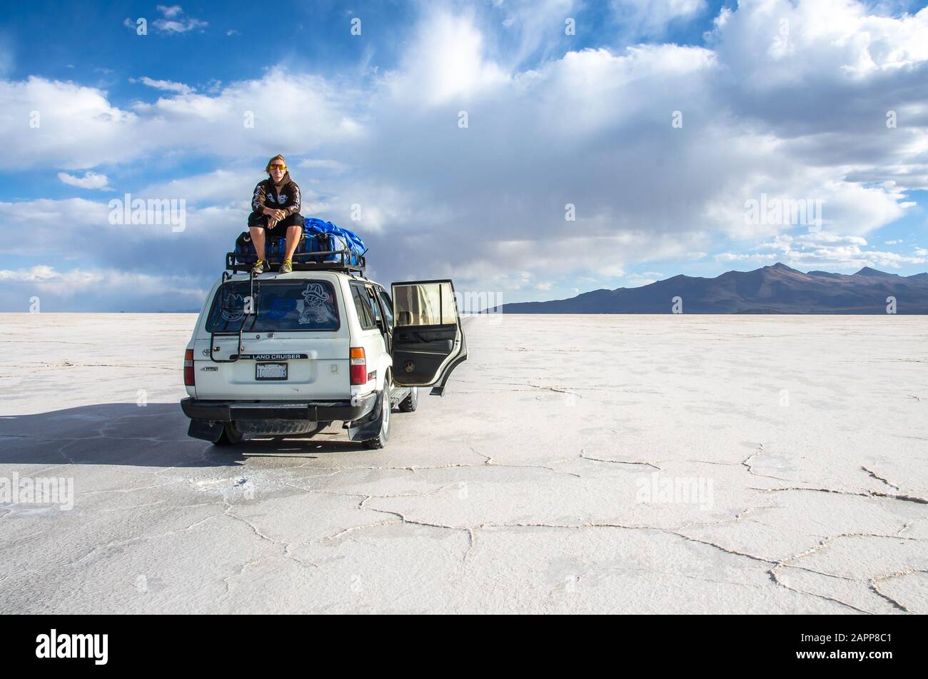 Salar de Uyuni in Bolivia covered with car and clouds. Girl standing on ...