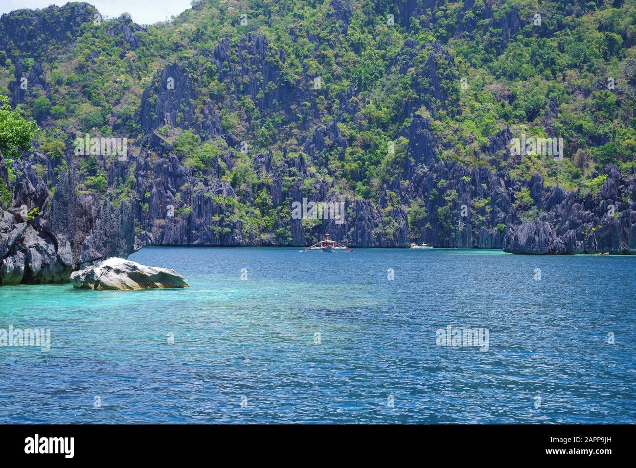 Paraw (double outrigger) boats sailing near big rocky island in the ...