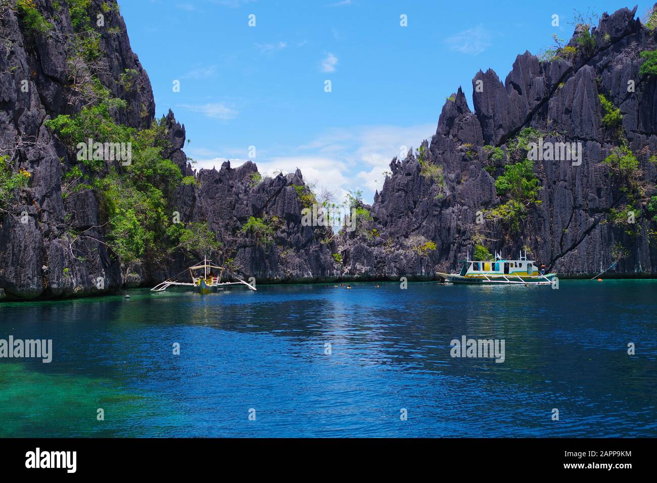 Paraw (double outrigger) boats sailing near big rocky island in the ...