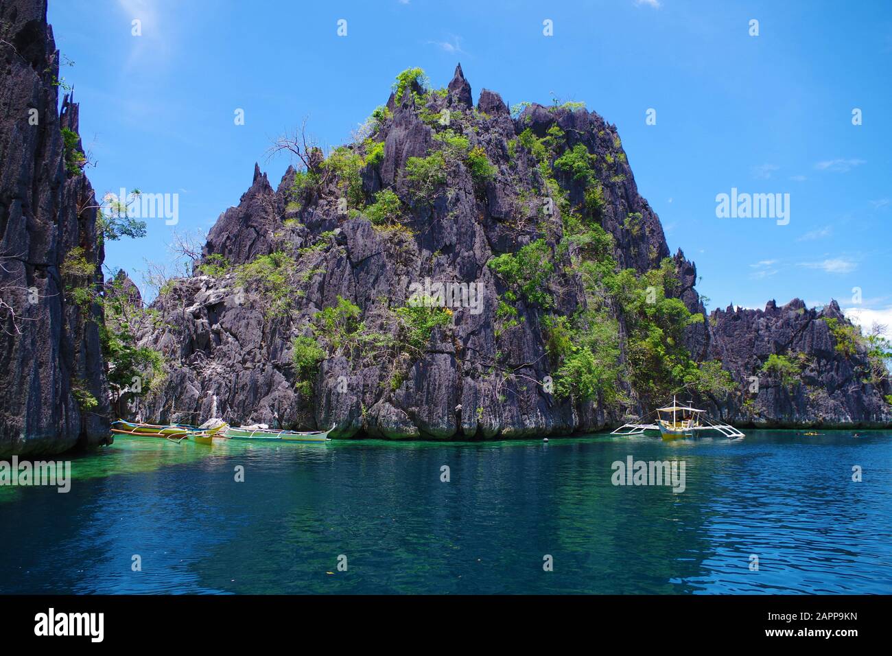 Paraw (double outrigger) boats sailing near big rocky island in the ...