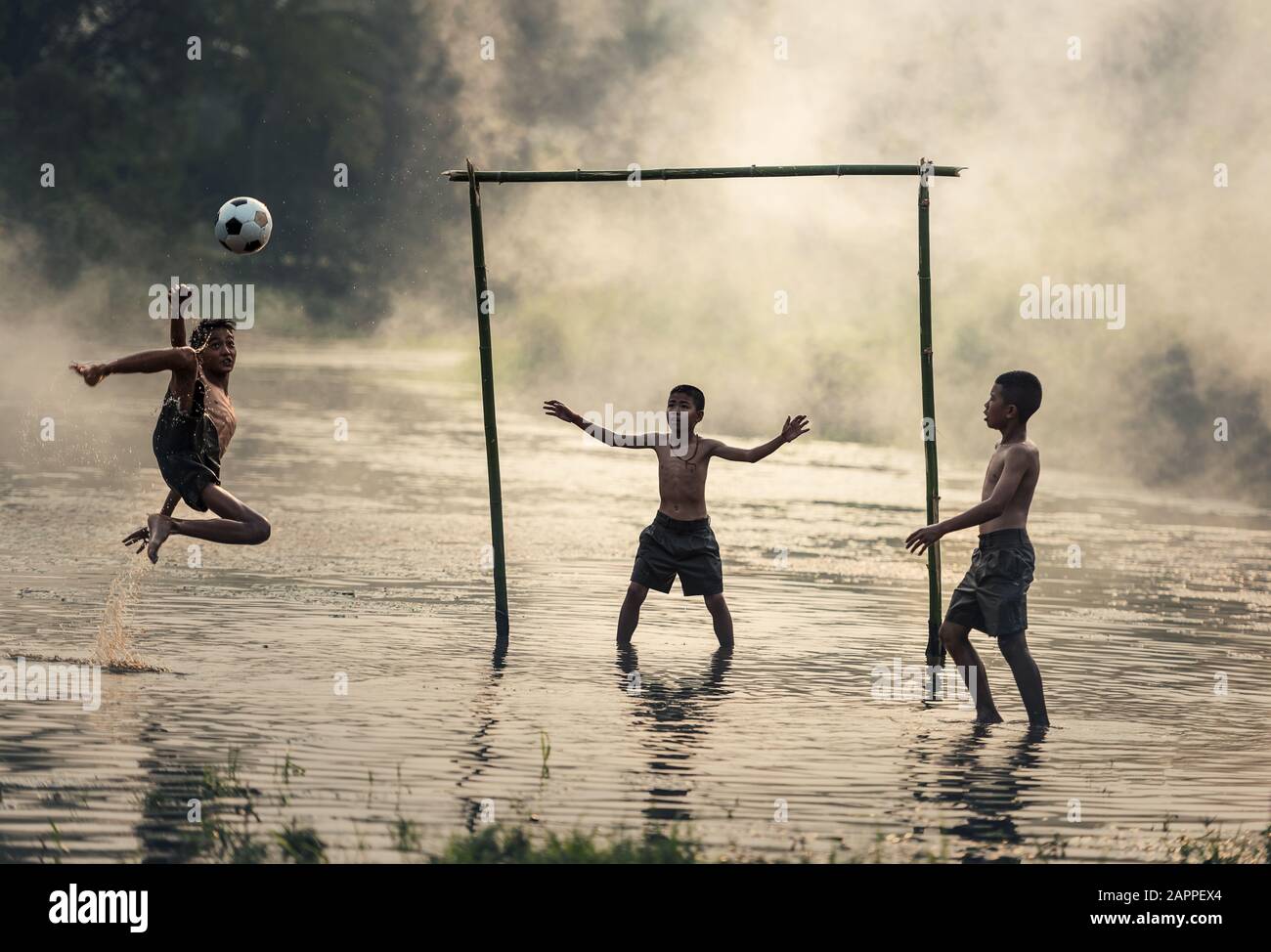 Boy kicking a soccer ball in the river Stock Photo - Alamy
