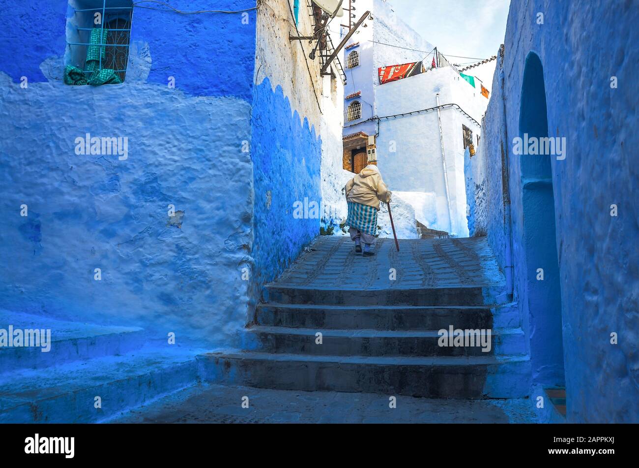 Woman in typical moroccan clothing, walking down a street in ...