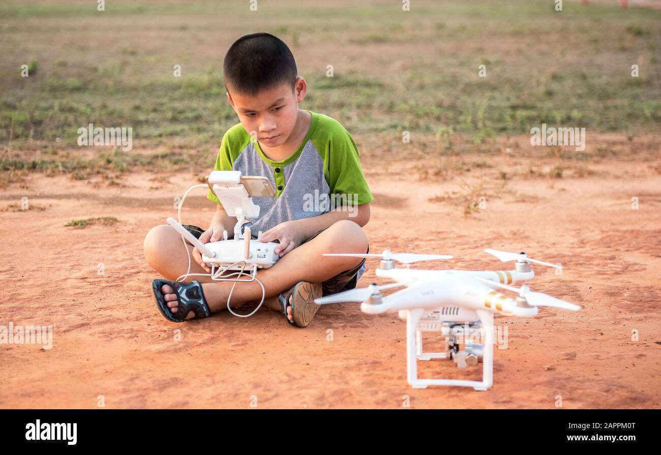 Portrait of kid with quadcopter drone outdoors. Happy boy playing with ...