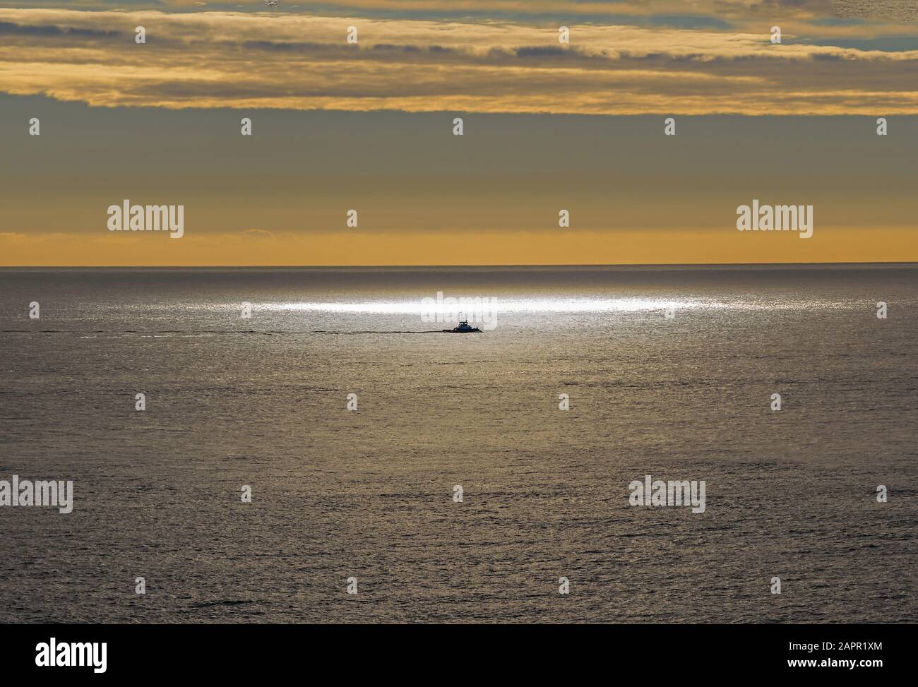 A lone Fishing boat by a sunburst spotlight shining on the Dorset sea ...