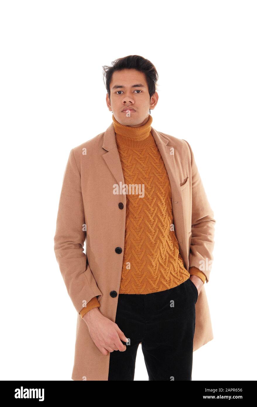 Handsome young man standing in a beige winter coat with one hand in his ...