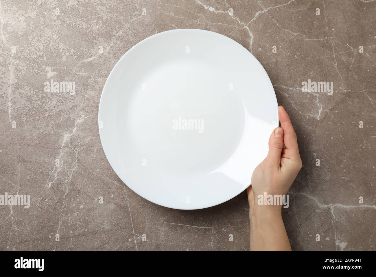 Female hand hold plate on grey background, top view Stock Photo - Alamy