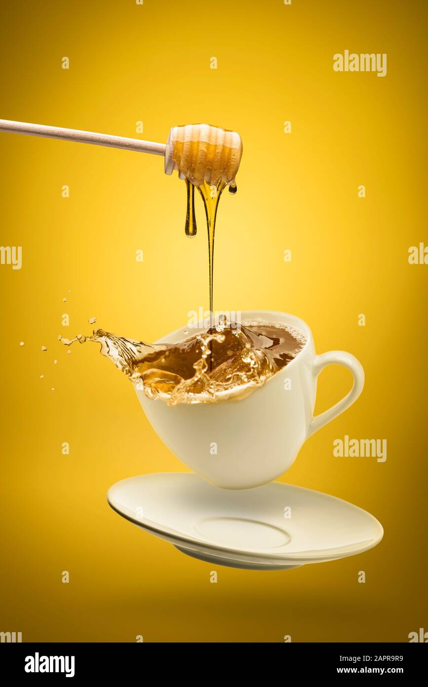 Honey dripping into cup of tea, on yellow background Stock Photo - Alamy