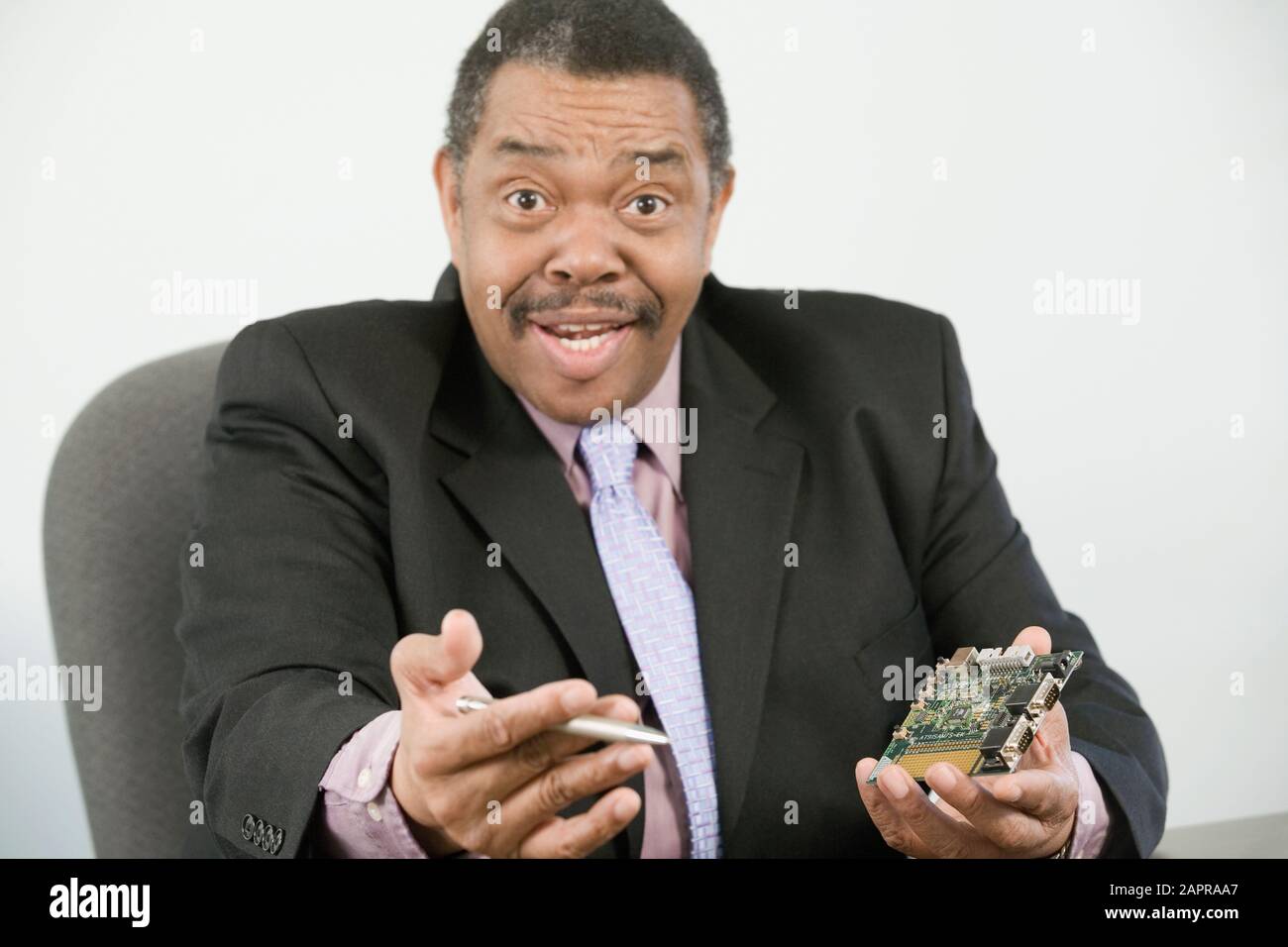 Portrait of a businessman holding a computer chip and a pen Stock Photo ...