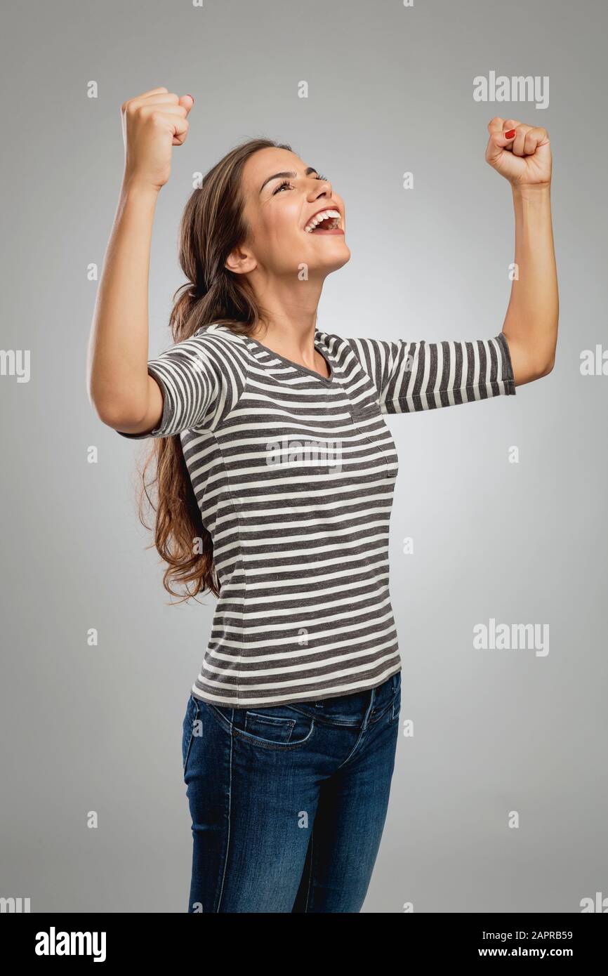 Portrait of a beautiful and successful young woman with raised arms ...