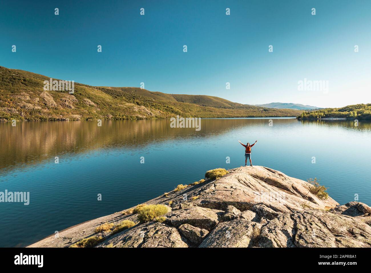 Shot of a man hiking near a beautiful lake with arsm raised Stock Photo ...
