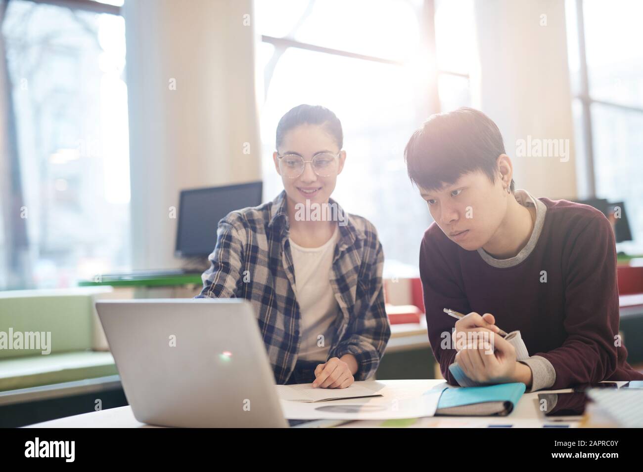Two students sitting at the table and using laptop computer in their ...