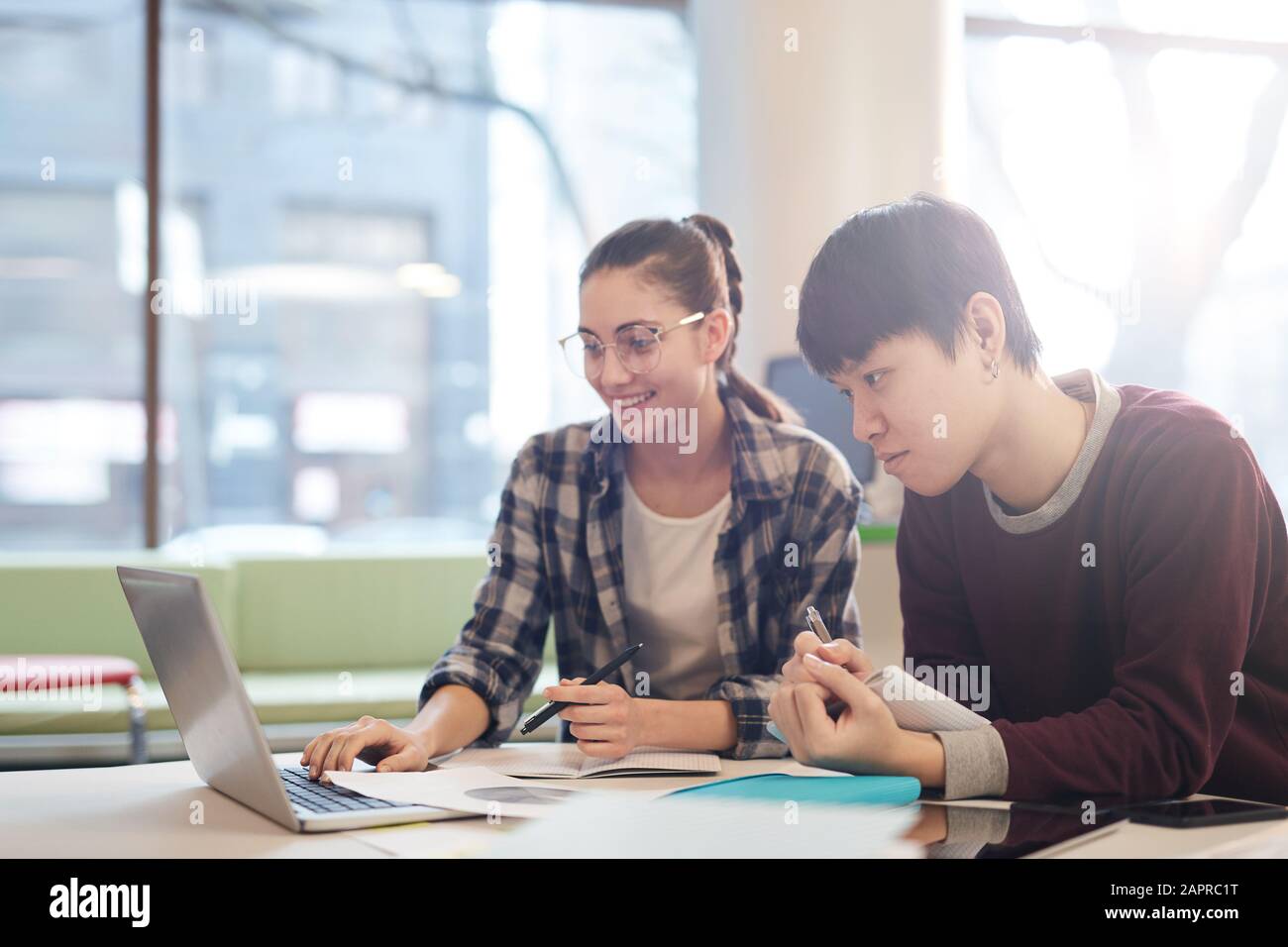 Two students sitting at desk looking at computer monitor and studying ...