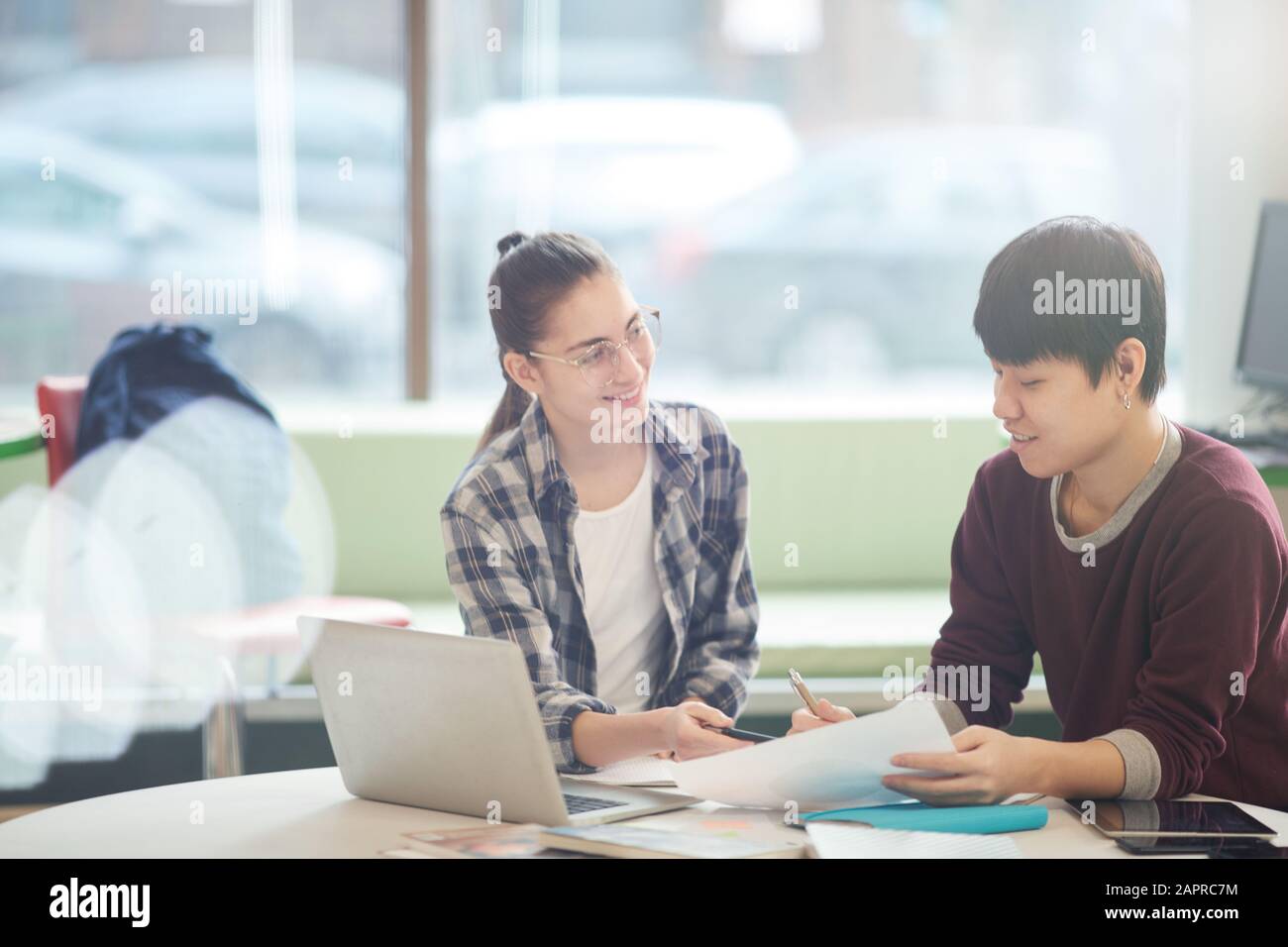 Two college students sitting at the table with laptop computer and ...