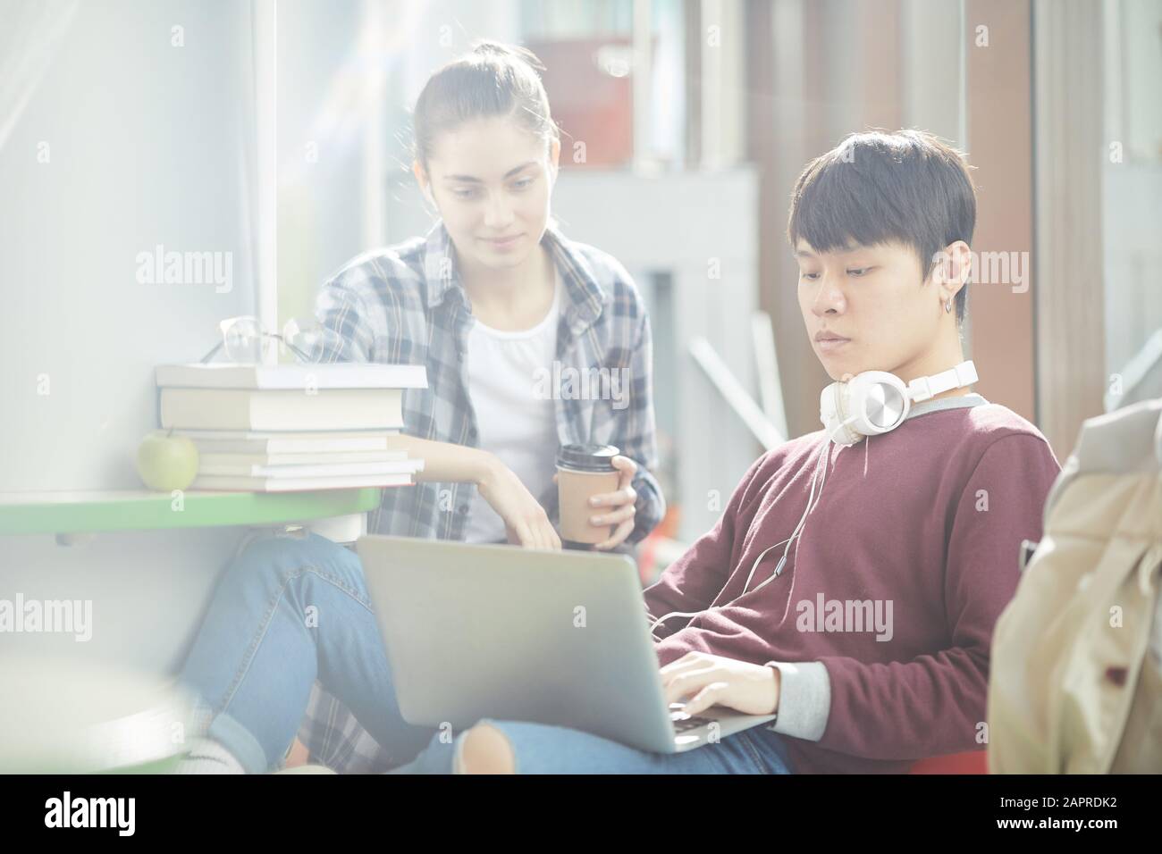 Asian boy sitting and typing on laptop computer while girl sitting near ...