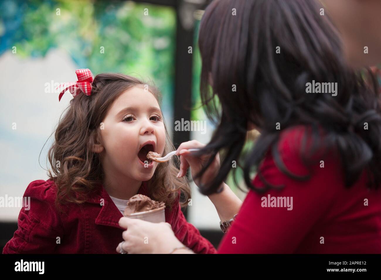 Mother feeding ice cream to young daughter Stock Photo - Alamy