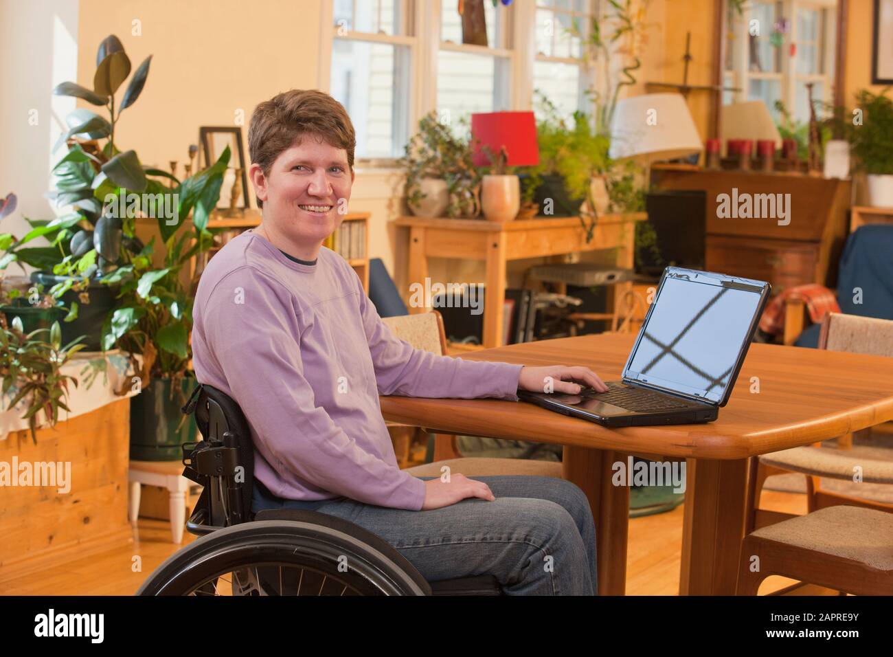 Disabled person in a wheelchair using a laptop at home Stock Photo - Alamy