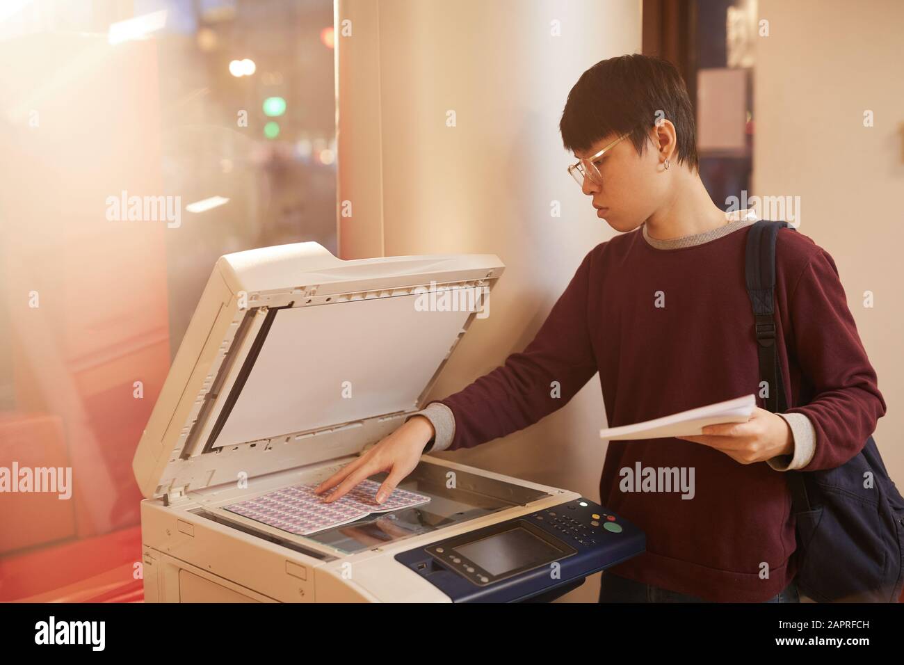 Asian college student making copy of new material using printer at ...