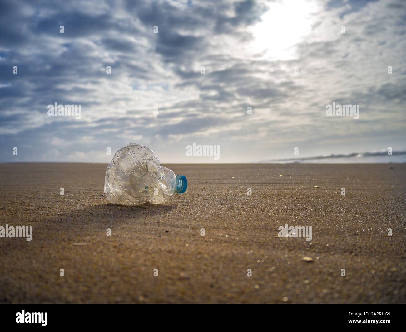 Plastic bottle dumped on the beach under a cloudy sky - plastic ...