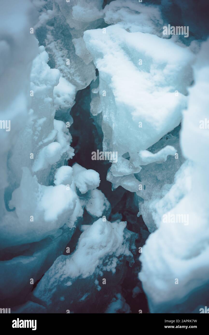 Vertical closeup shot of an ice crevasse in the snowy covered ground ...