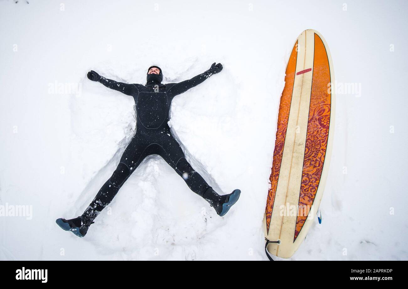Surfer makes snow angel in Maine winter snow storm Stock Photo - Alamy