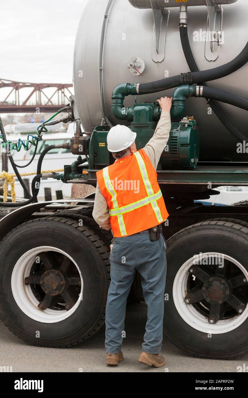 Environmental engineer adjusting pump on tanker truck at waste cleanup ...