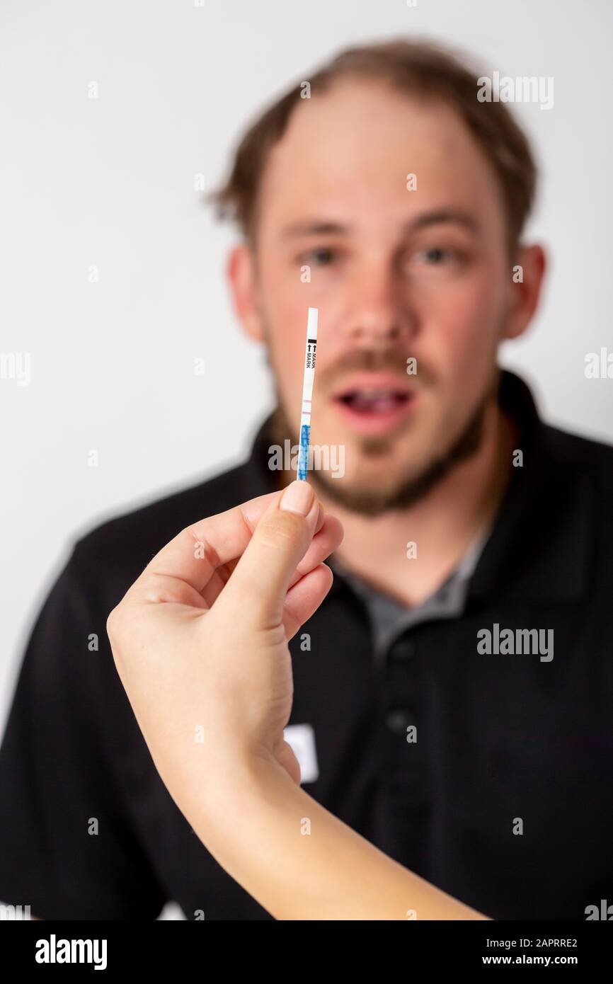 Positive Pregnancy Test Held By A Surprised Man In The Background Stock