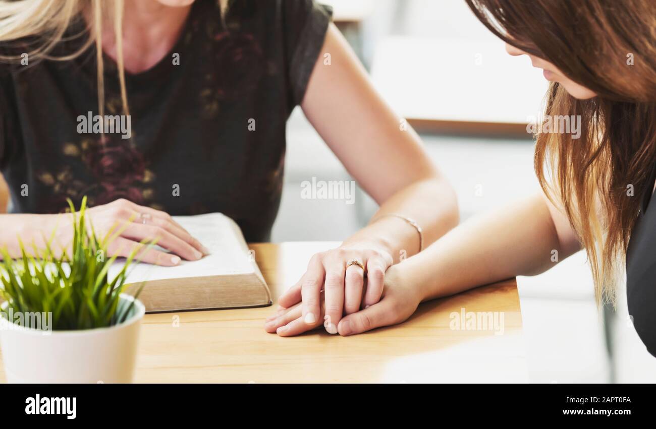 A mature Christian woman mentoring and praying with a young woman ...