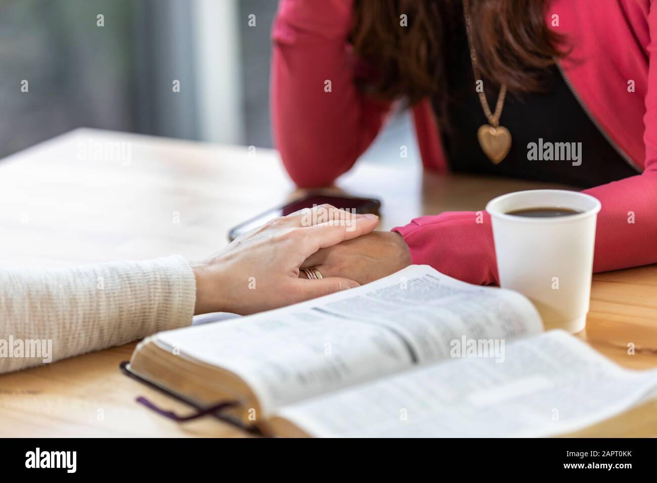 A mature Christian woman mentoring and praying with a young woman ...