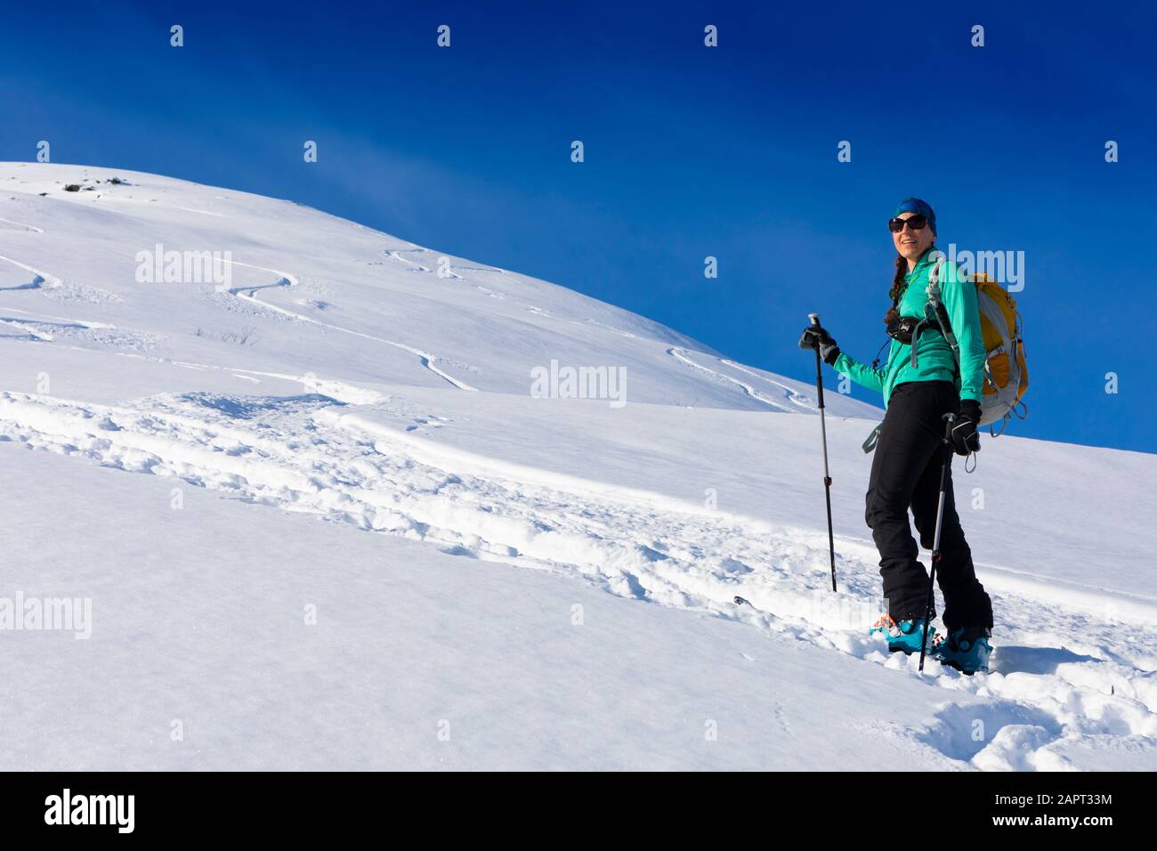 Woman backcountry skiing, climbing up mountain in skin track, on AT ...