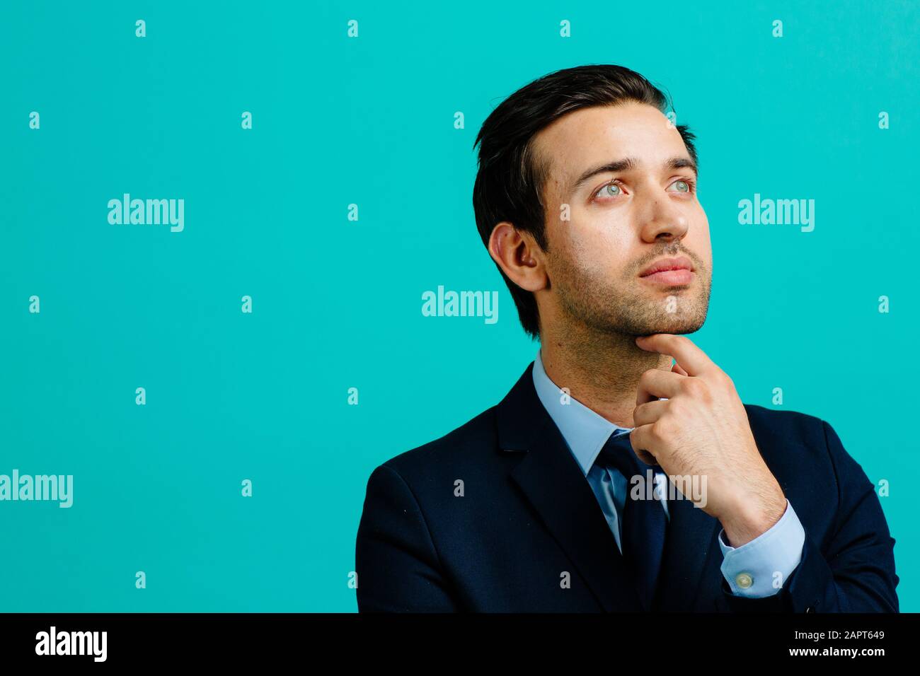 Portrait of a young entrepreneur business man thinking with hand under ...