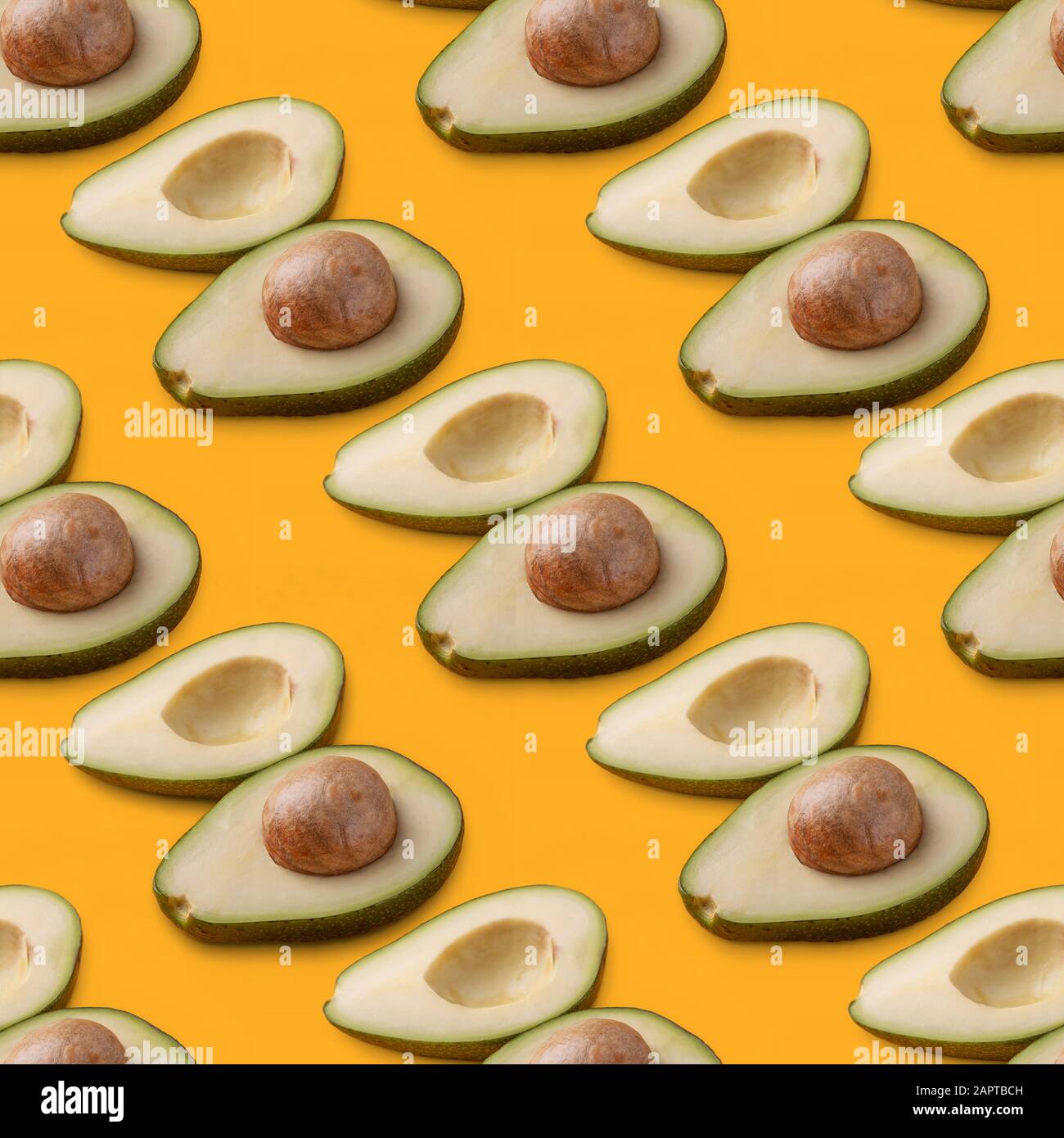 Avocado halves with kernels pattern on orange background Stock Photo ...
