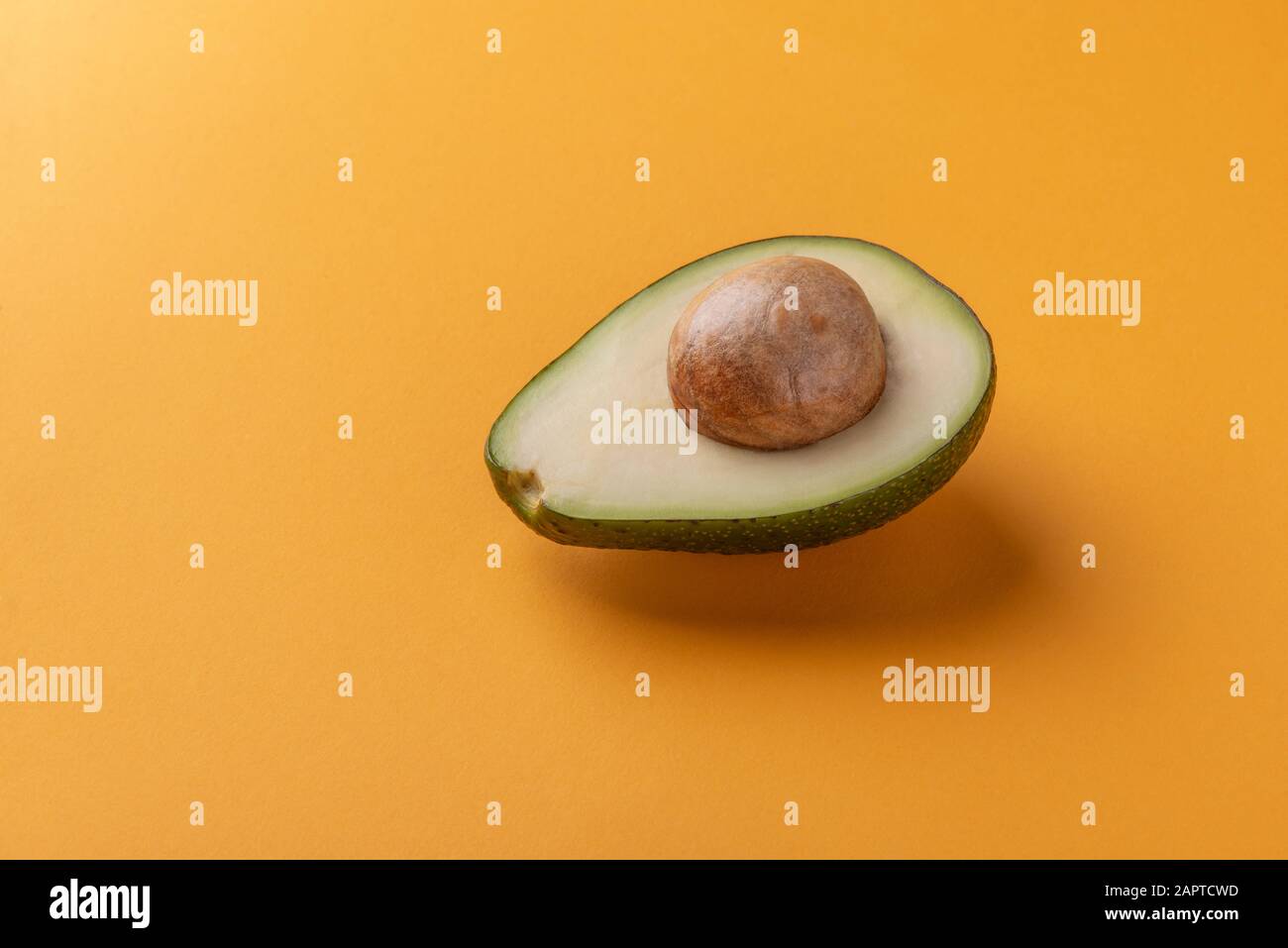 Avocado half with kernel on orange background. Tropical fruit Stock ...