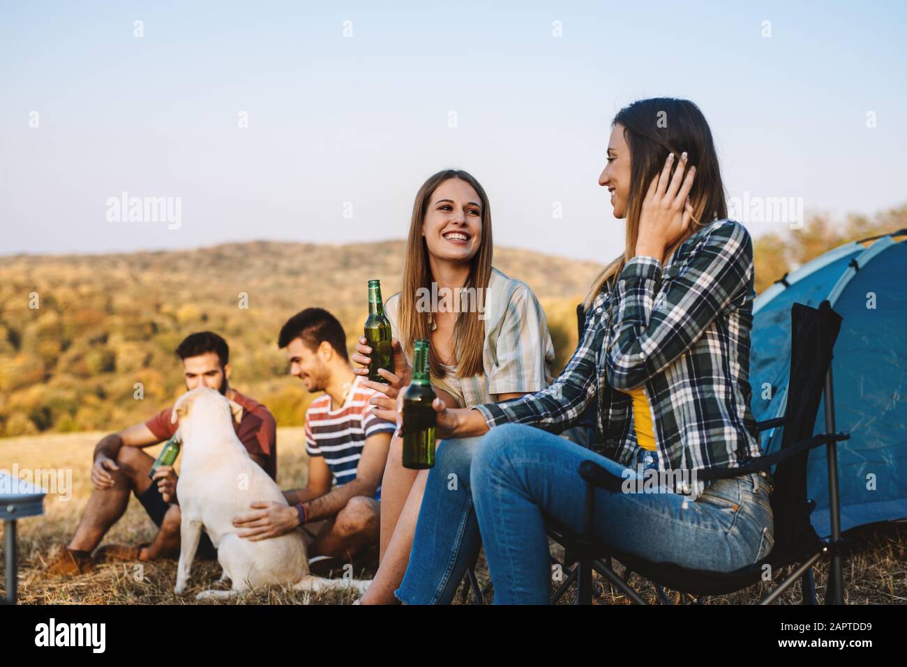 Portrait of cheerful young friends hanging out with beers. Group of ...