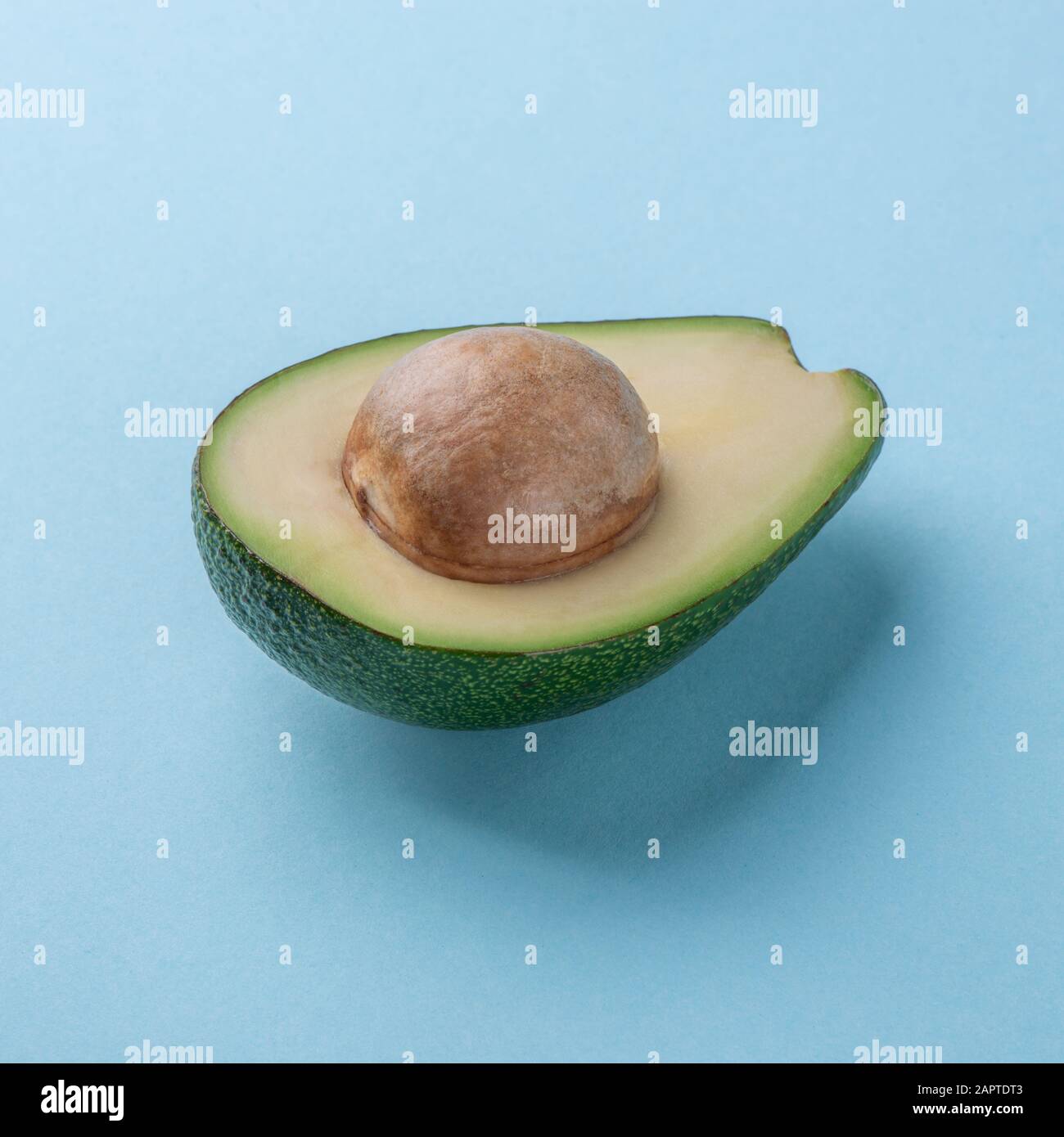 Avocado half with kernel on blue background Stock Photo - Alamy