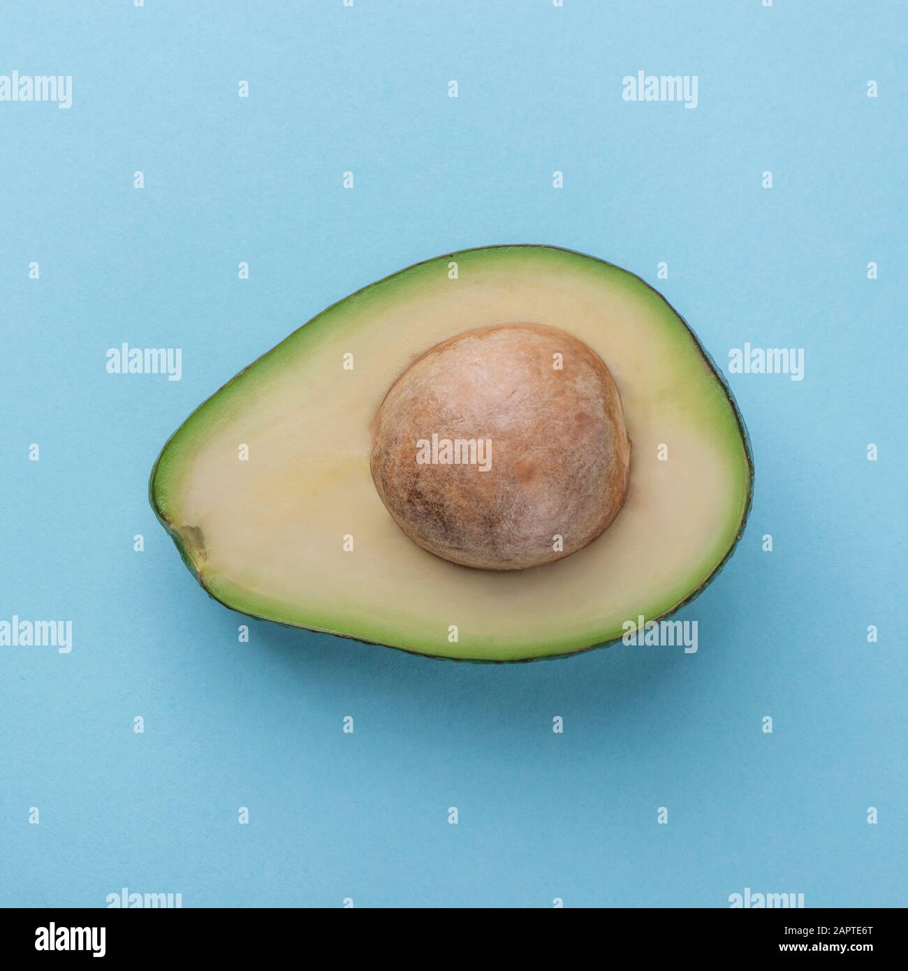 Avocado half with kernel on blue background Stock Photo - Alamy