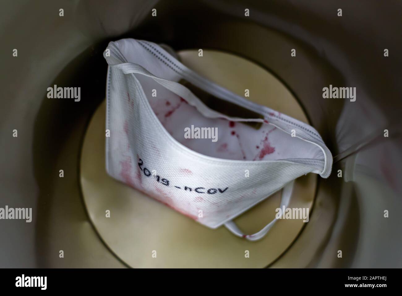 Bloody safety mask thrown away in a trash after a 2019-nCOV coronavirus ...