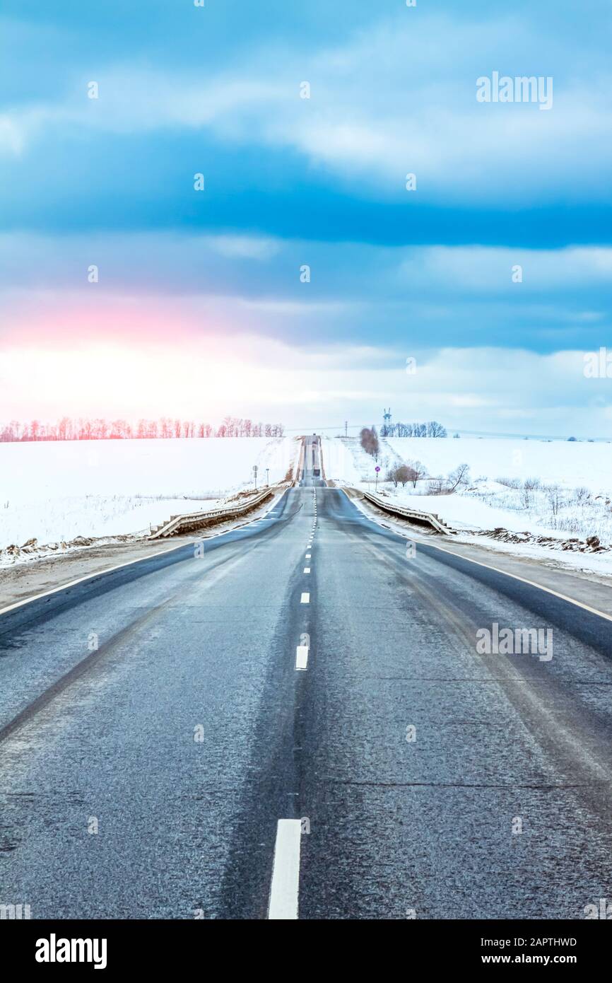Winter road going over the horizon. Blue clouds above the road Stock ...